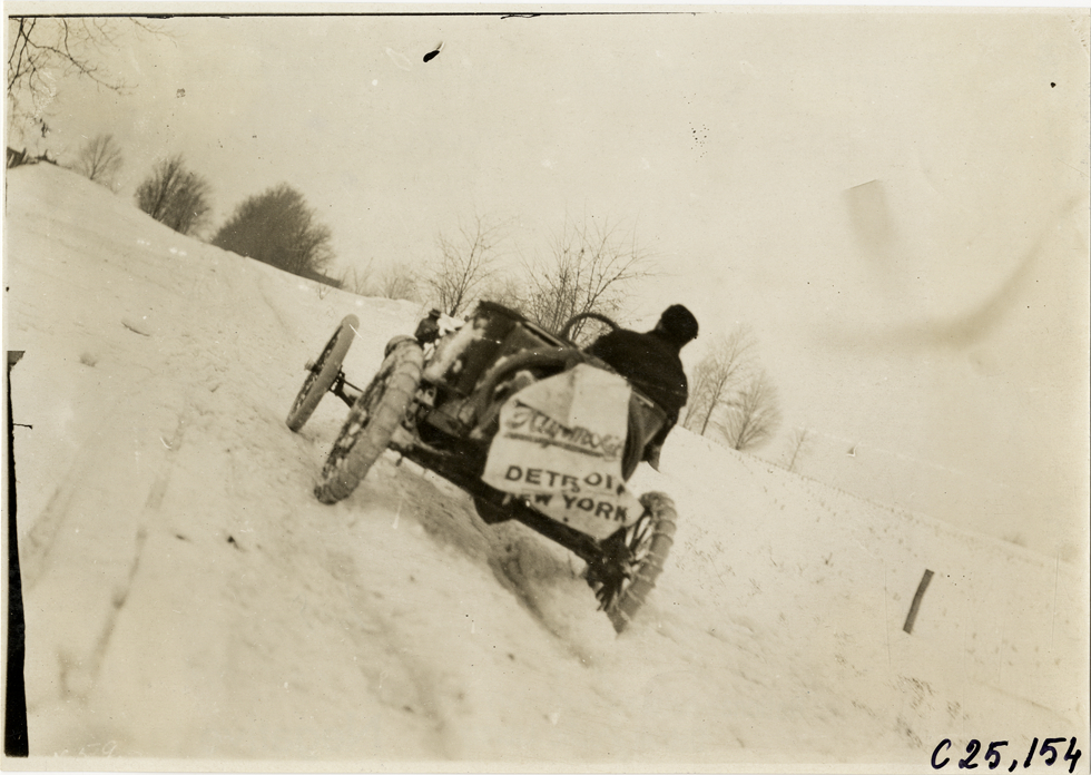 Driver in Hupmobile automobile traveling on snow-covered road, 1910 ...