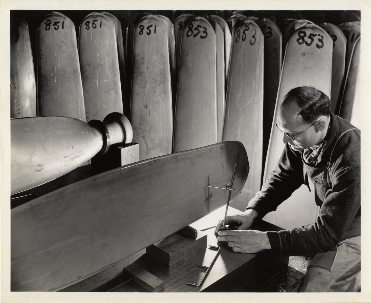 Metal worker performing final inspection on aircraft propeller blade ...